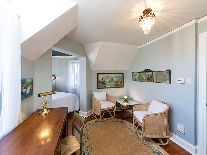 The attic suite's serene blue walls and vintage furnishings create a peaceful retreat that's less "forgotten storage space" and more "exclusive penthouse getaway."