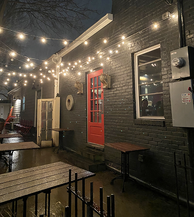 By night, the exterior transforms into a twinkling pizza oasis. That red door practically begs you to enter pizza paradise.
