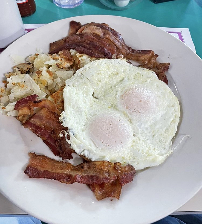 The breakfast of champions: eggs with perfect sunny centers, bacon crisped to perfection, and hash browns that crackle with each delicious bite.