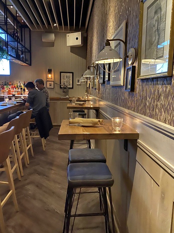 Counter seating along the wall offers front-row views of culinary magic while textured wallpaper adds subtle sophistication to casual dining.