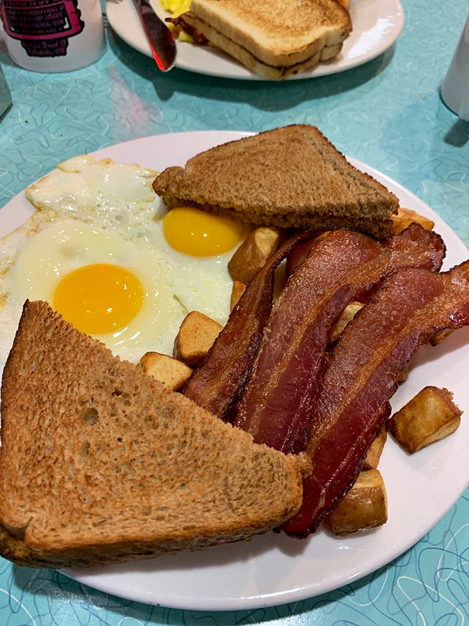The breakfast trinity: perfectly cooked eggs, bacon with the ideal crisp-to-chew ratio, and toast standing by to soak up that golden yolk.