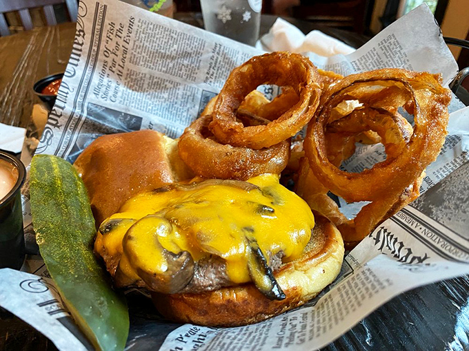 A burger and onion rings that remind you why simple pleasures endure—melty cheese cascading down a hand-pressed patty like a yellow waterfall.