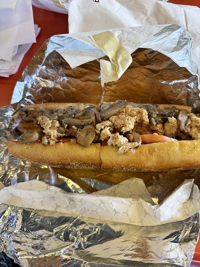 A cheesesteak that refuses to be contained by mere aluminum foil. The mushrooms and meat spill out like they're making a break for freedom.