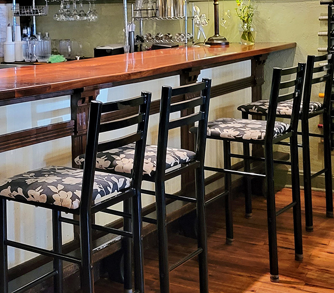 Counter seating with floral-patterned cushions offers front-row tickets to the culinary show happening just beyond those wooden barriers.
