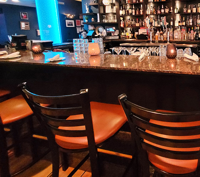 Bar seating with orange cushions provides front-row seats to watch the kitchen magic happen in comfort.