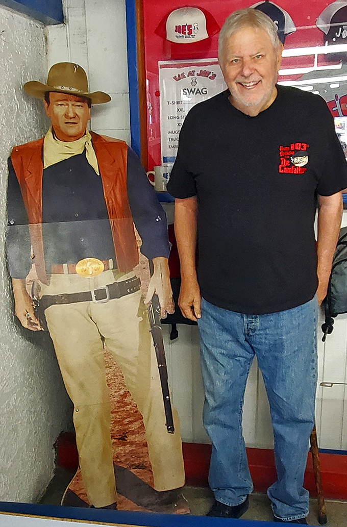 The diner features a life-sized cutout of John Wayne alongside a smiling patron, proving that both cowboys and locals recognize good eating.