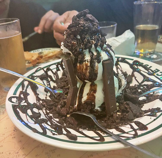 This isn't just dessert—it's a chocolate skyscraper of ice cream, brownie, and sauce that requires both a spoon and a strategic eating plan.