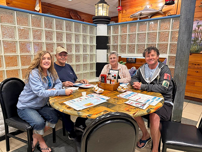 Happy diners gathered around a lighthouse-themed table &ndash; the universal expression of "we ordered exactly right" on every face.