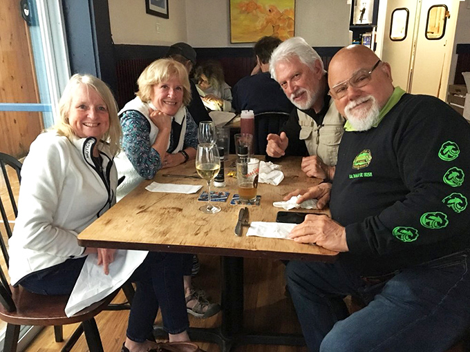 Happy diners sharing stories and seafood—the universal language of a great meal that transcends the humble surroundings and creates lasting memories.