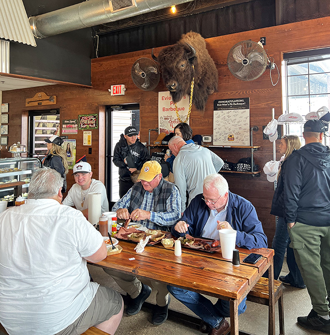 The universal language of barbecue brings folks together at wooden tables where conversation flows as freely as the sweet tea.