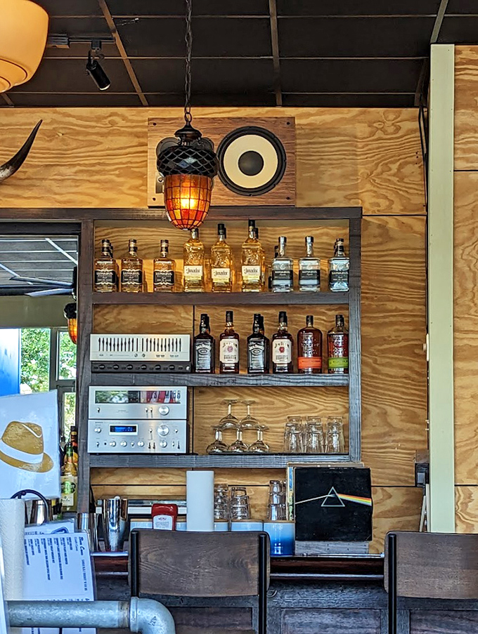 Bourbon bottles displayed like trophies on wooden shelves. That pendant light casts the kind of glow that makes everyone look like they're in a food commercial.