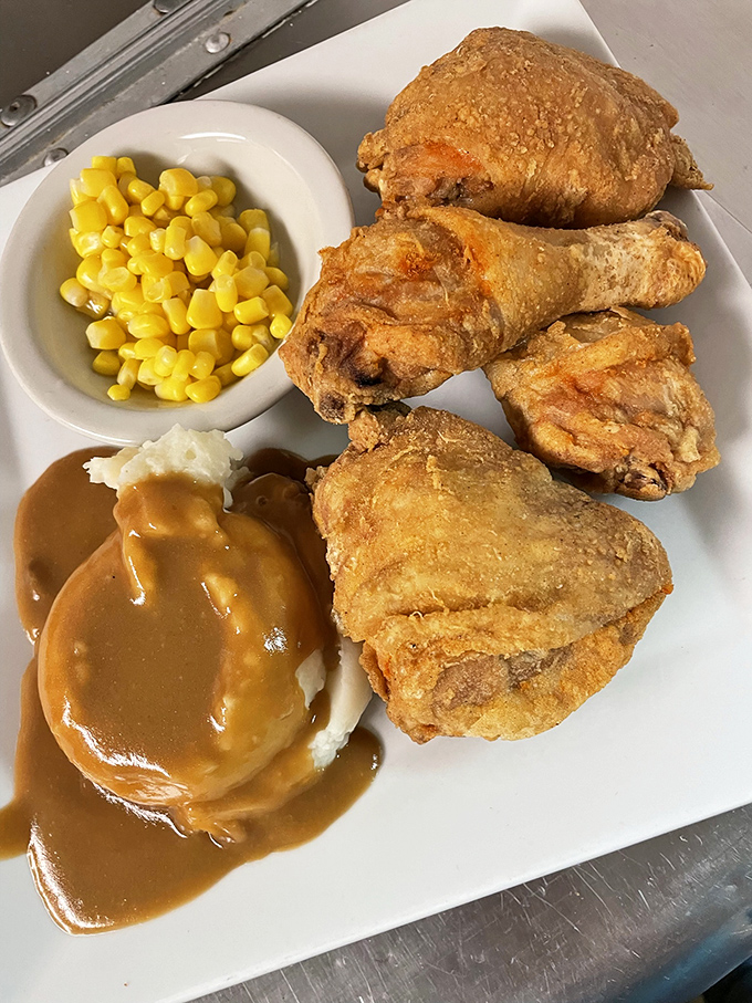 Fried chicken with a golden crust that crackles like radio static, alongside mashed potatoes drowning happily in gravy.