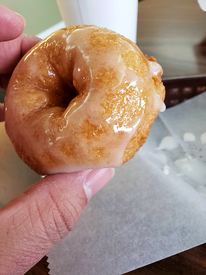 The perfect glazed donut caught mid-bite—that moment when the world stops and nothing matters except the warm, sweet perfection in your hand.