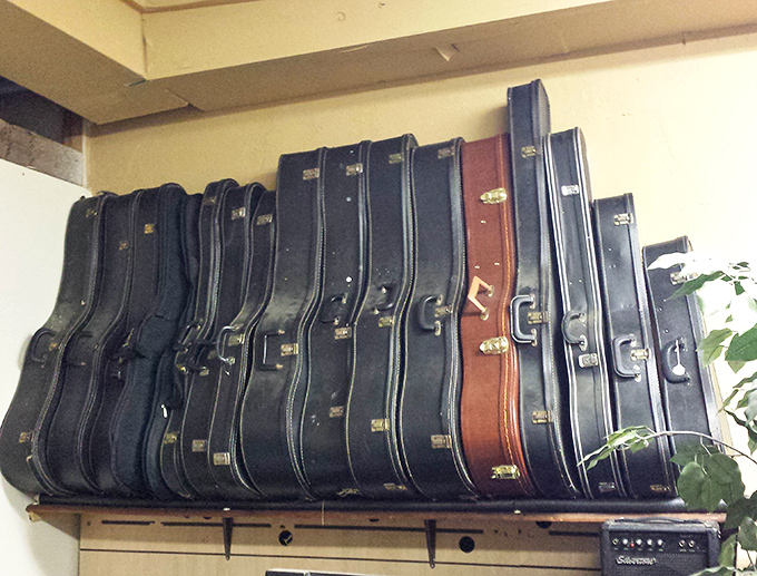 Guitar cases line the wall like soldiers at attention—each potentially housing an instrument that once played someone's life soundtrack.