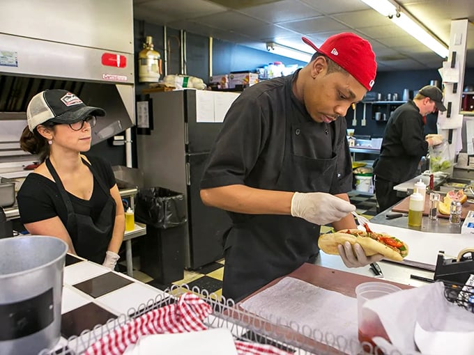 Sandwich artistry in action! The focused craftsmanship behind the counter at Gaudiello's proves that true culinary magic happens when skilled hands meet quality ingredients.