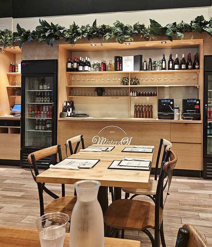The bar area whispers "stay awhile" with its warm wood tones and carefully curated wine selection. Even the plants look happy to be here.