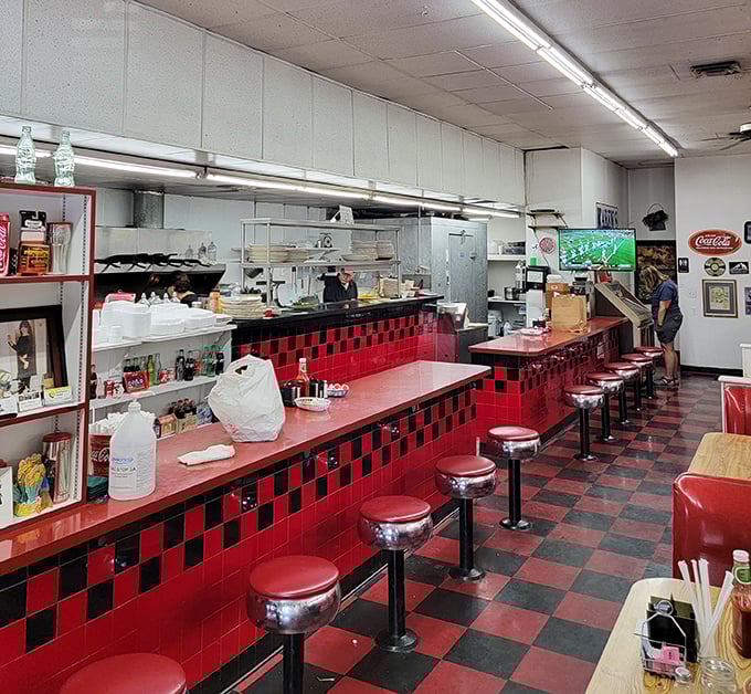 The counter seating offers front-row tickets to the breakfast show, where short-order magic happens against the backdrop of red and black tiles.