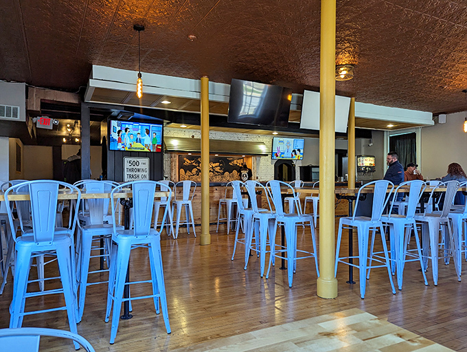 The copper ceiling reflects warm light onto blue metal chairs, creating the kind of space where you'll want to linger long after your burger is gone.