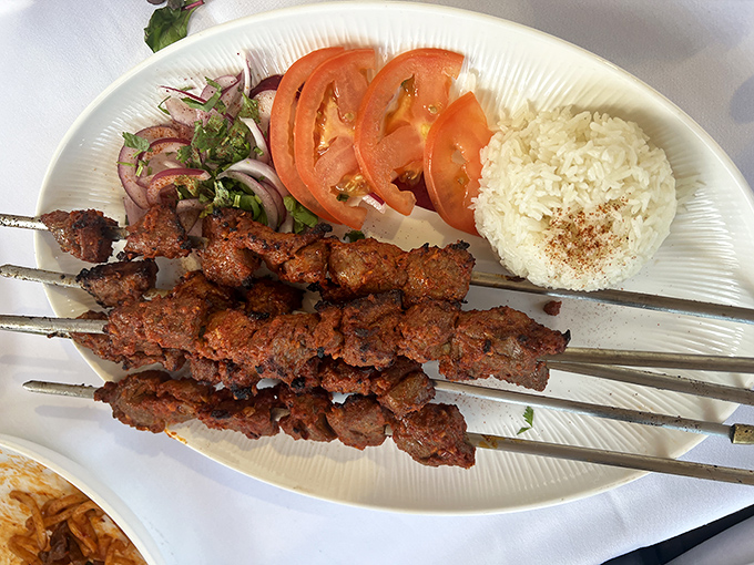 Perfectly grilled kebabs arrive with vibrant vegetables and aromatic rice&mdash;a simple yet profound reminder of why this cooking technique has endured for centuries.