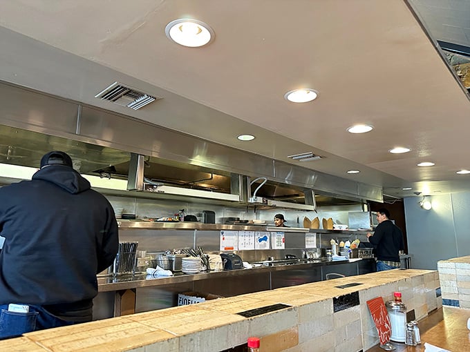 The open kitchen operates like culinary theater, where chefs perform their craft under the spotlight of hungry eyes and high expectations.