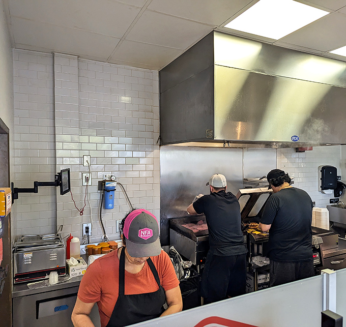 Where the magic happens! Dedicated hands working the grill, creating those perfect smash burgers with practiced precision and care.