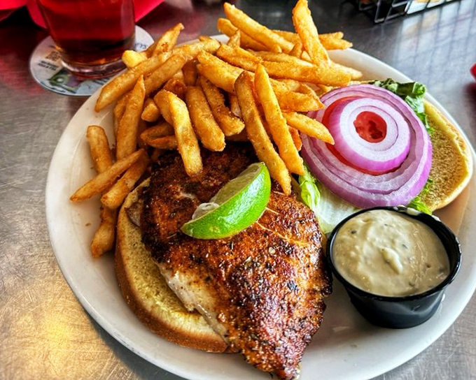 This blackened fish sandwich isn't messing around&mdash;crispy fries, tangy sauce, and a lime wedge standing by for emergency flavor deployment.