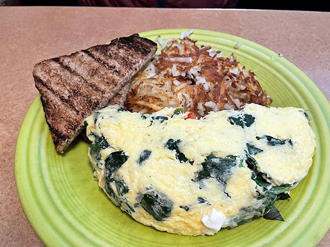 This isn't just an omelet&mdash;it's a fluffy yellow canvas painted with vibrant spinach, served alongside crispy hash browns and hearty toast.