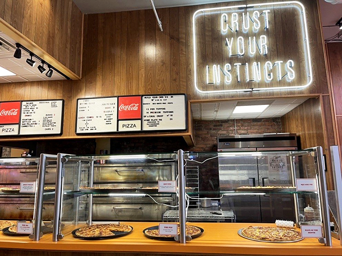 "Crust Your Instincts" glows above the pizza display—sage advice for life and lunch decisions in downtown Cleveland.