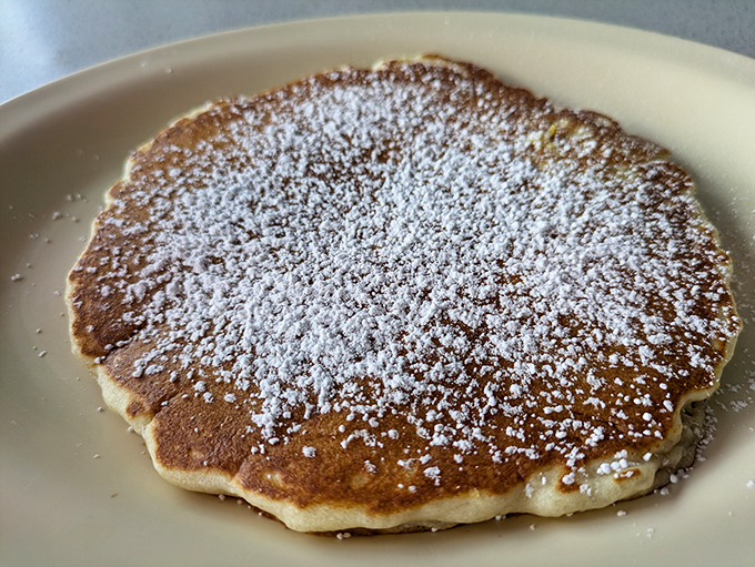 This pancake isn't just dusted with powdered sugar &ndash; it's wearing a delicate snowfall that transforms breakfast into an occasion.