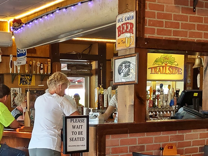 The bar's vintage signs and glowing lights create that magical hour when hunger meets anticipation. The "Please Wait to Be Seated" sign is just a pause before joy.