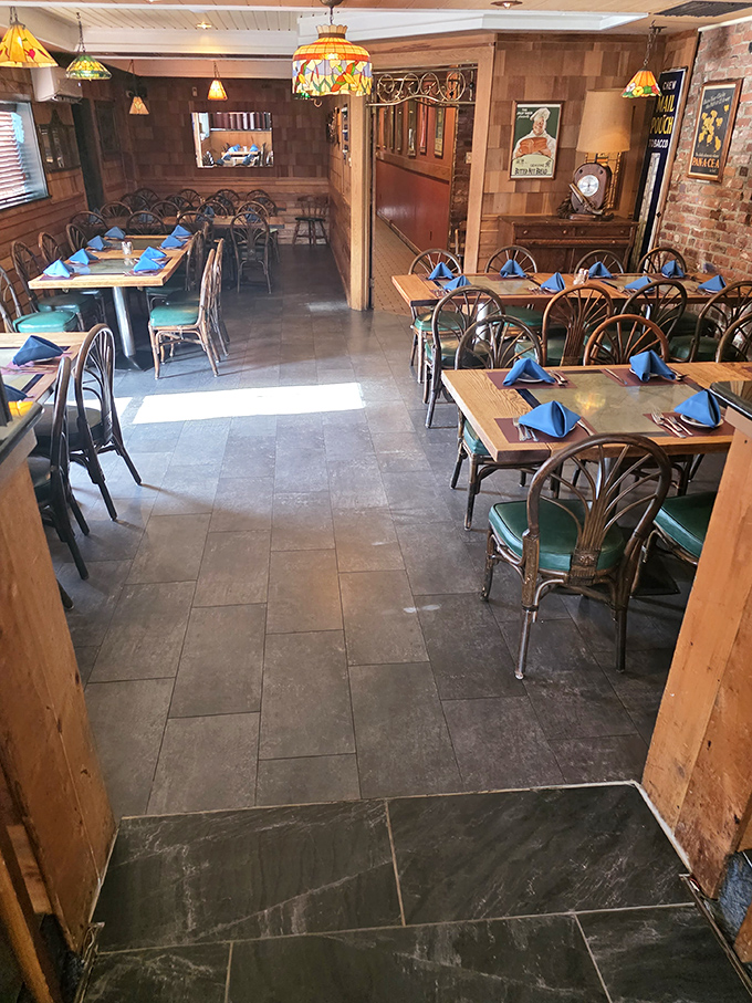 Tiffany-style lamps cast a warm glow over tables set with blue napkins. The dining room waits expectantly for the evening's stories to unfold.