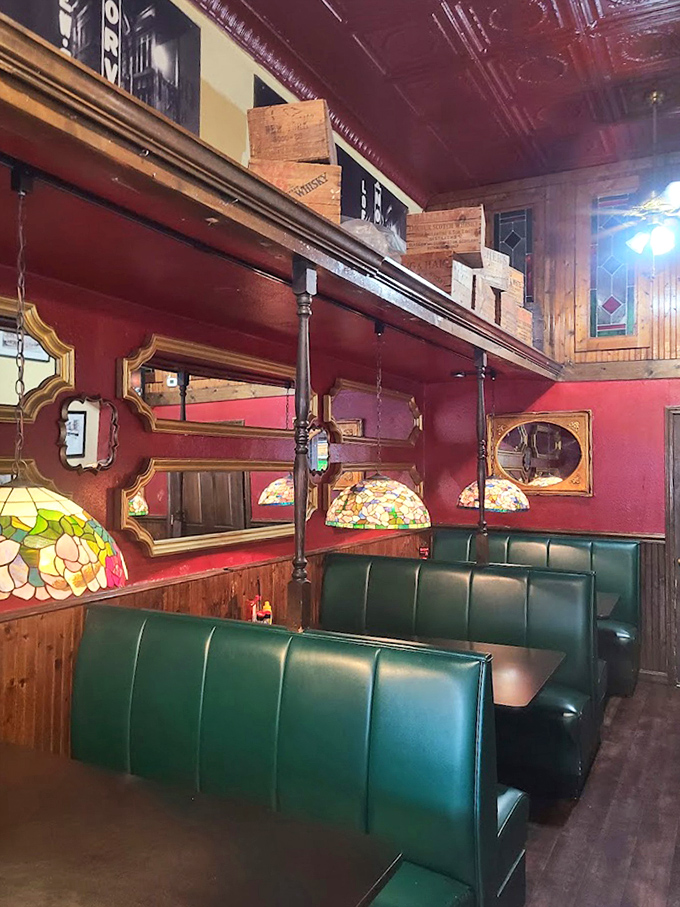The dining area's green booths and Tiffany-style lamps create intimate spaces for conversation, while vintage mirrors add character to the warm atmosphere.