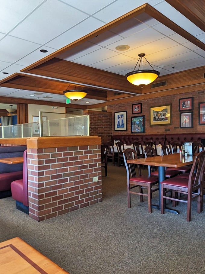 Brick dividers create intimate dining zones without sacrificing the classic steakhouse atmosphere. Those burgundy chairs have supported generations of satisfied customers.