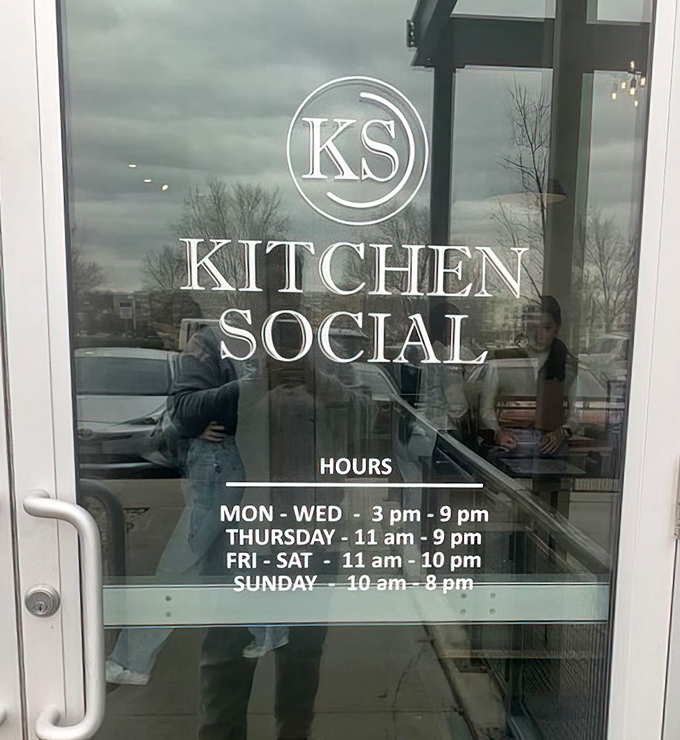 Hours posted like an invitation to happiness. The glass door reflection hints at the community that's formed around these carefully crafted meals.