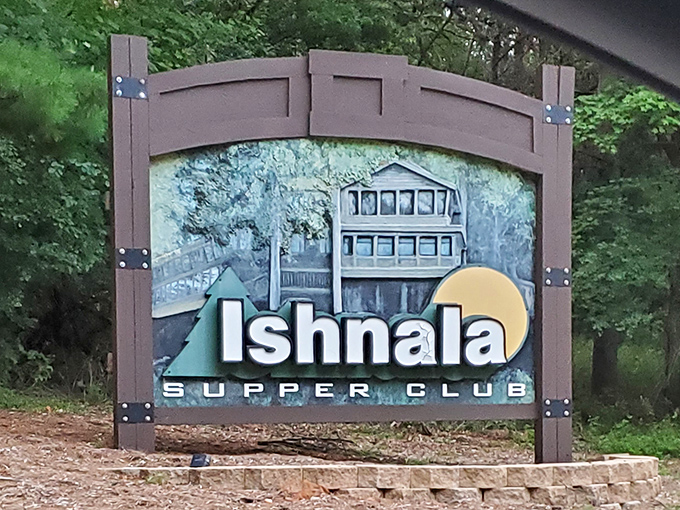 The sign that's launched a thousand dinner pilgrimages, standing sentinel at the edge of the forest like a tasty treasure map.