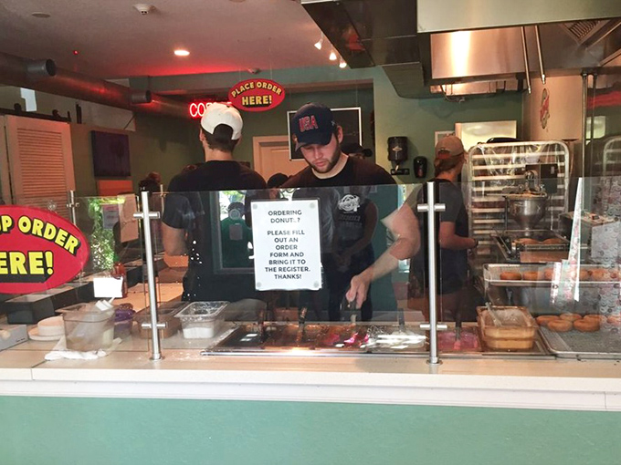 Behind the glass, donut artists transform simple rings of dough into edible masterpieces that would make Picasso trade his paintbrush for sprinkles.