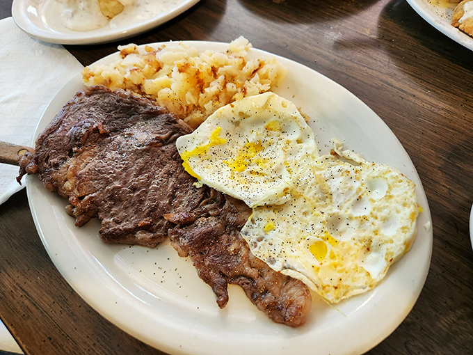Steak and eggs: the breakfast of champions who plan to skip lunch, featuring a perfectly cooked sunny-side up egg and home fries that demand to be devoured.