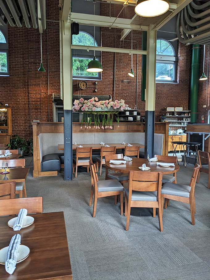 Fresh flowers and thoughtful table settings prove that industrial spaces can still feel intimate. Those wooden chairs have heard more food revelations than a confessional.