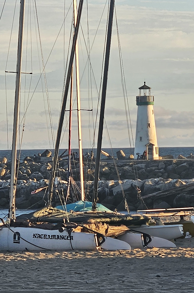The perfect framing: sailboat masts in the foreground create leading lines that draw your eye directly to the lighthouse's pristine silhouette. 