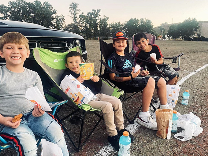 Young cinema connoisseurs setting up their viewing headquarters with snacks strategically positioned for optimal movie marathon endurance.