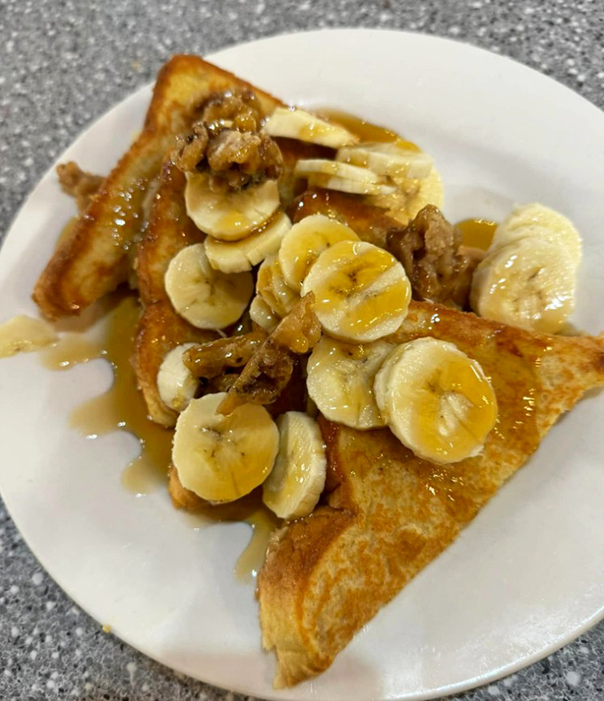 French toast transformed into a banana walnut masterpiece. Breakfast or dessert? The line blurs deliciously as maple syrup cascades down golden slopes.