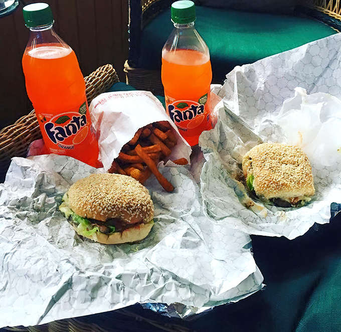 Two sesame seed buns cradling fresh ingredients, with crispy fries and orange Fanta. A lunch that speaks to your inner child.