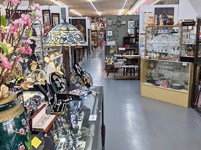 Tiffany-style lamps cast colorful shadows over glass cases filled with memories. The wide aisles invite you to take your time exploring each vendor's treasures.