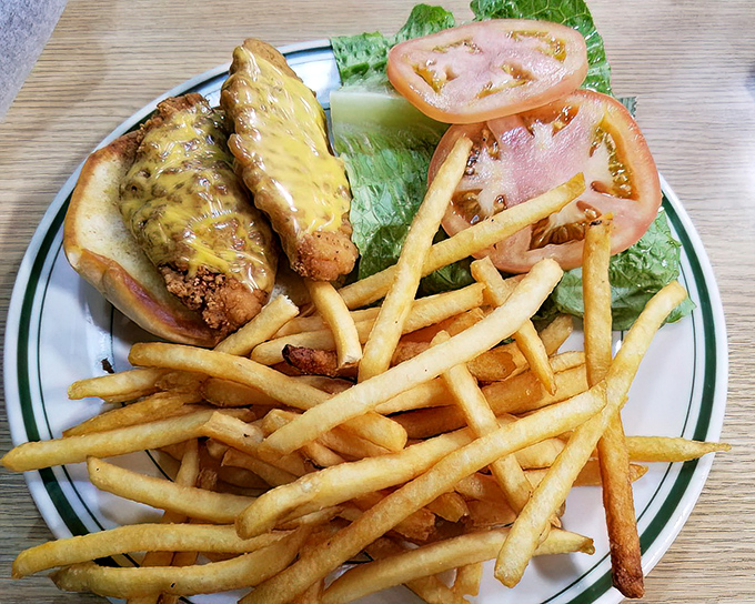 Golden-fried chicken fingers nestled in a bun with melted cheese and crispy fries standing guard. Comfort food that speaks directly to your inner child.