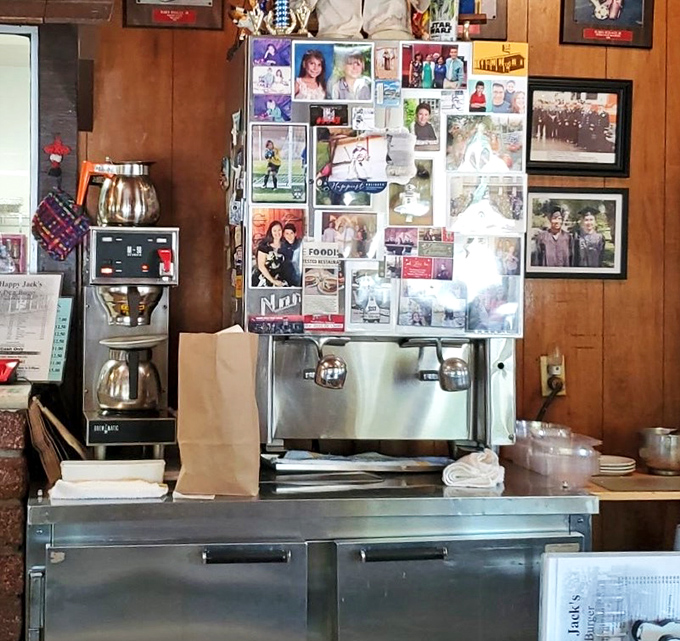 The coffee station, adorned with community photos, serves as both beverage source and unofficial town bulletin board—caffeinating conversations since day one.