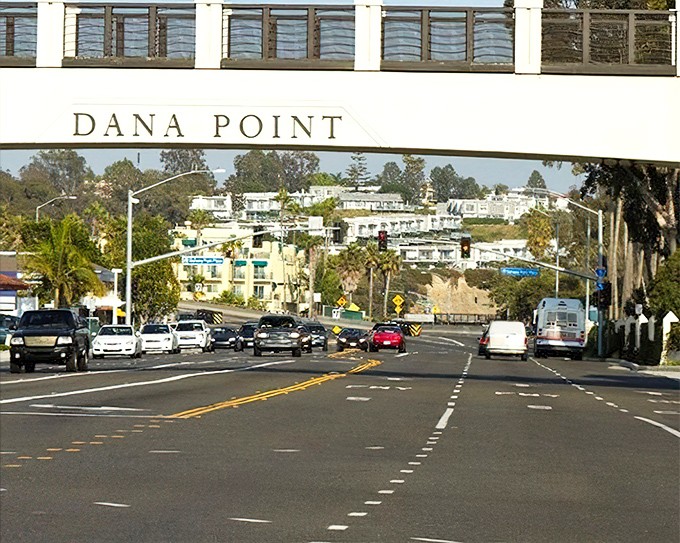 The Dana Point sign spans Harbor Drive, a symbolic gateway between everyday life and the coastal paradise that awaits just beyond.