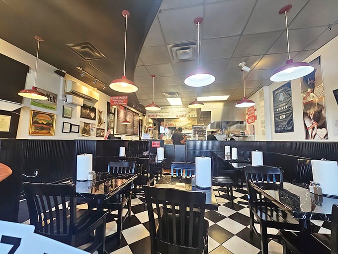 Classic black and white checkered floors, red pendant lights, and tables numbered for burger delivery precision. Nostalgia meets efficiency in the best way.