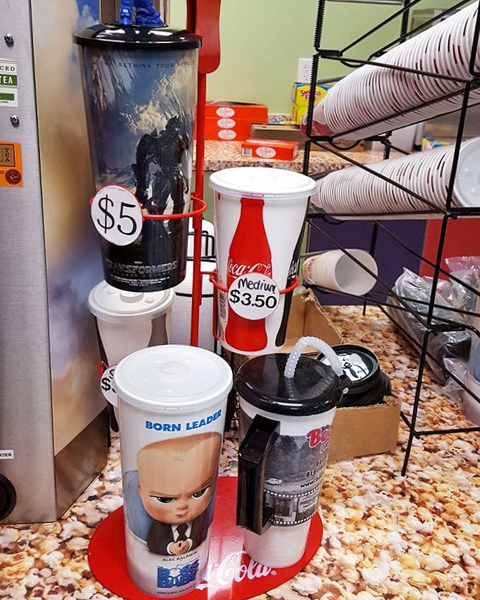 Drink cups stack high beside the popcorn machine, ready for sodas that somehow taste better outdoors.