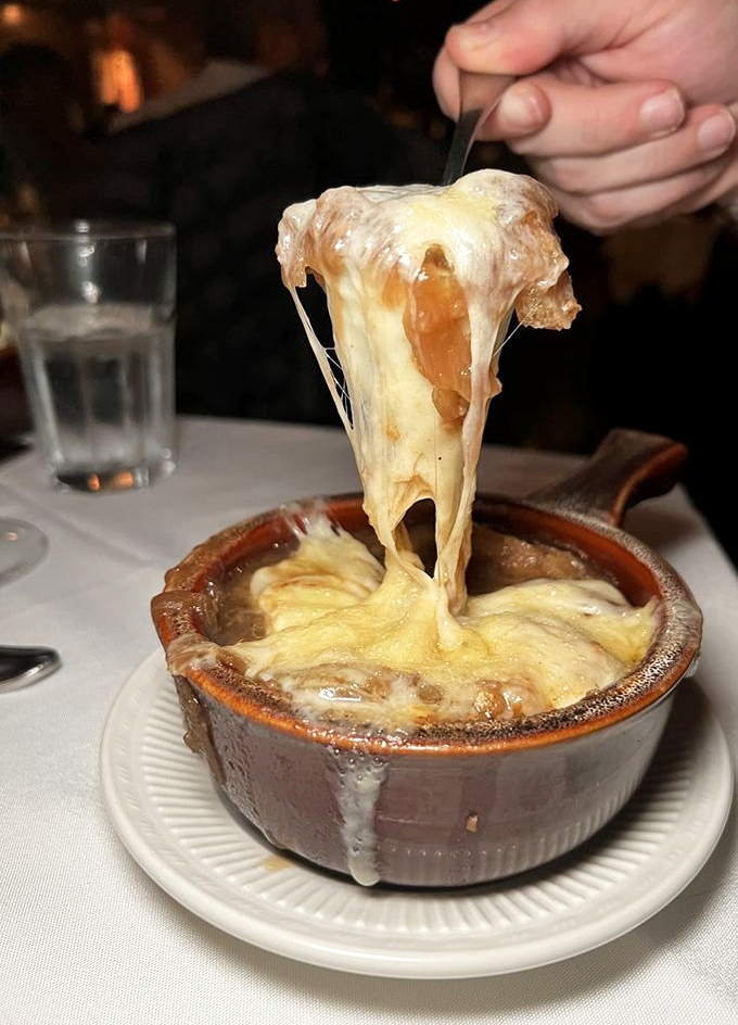 French onion soup with cheese that performs an acrobatic stretch worthy of an Olympic gold medal.