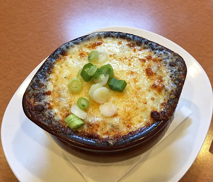 French onion soup that's wearing its cheese crown with pride. Those green onions are the confetti at this flavor party.